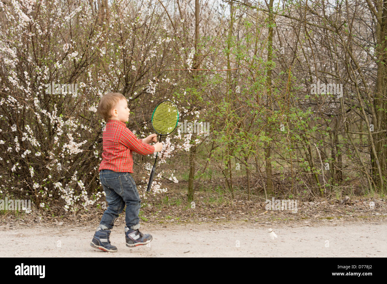 Little boy playing in a park with spring blossom holding out his hands ...