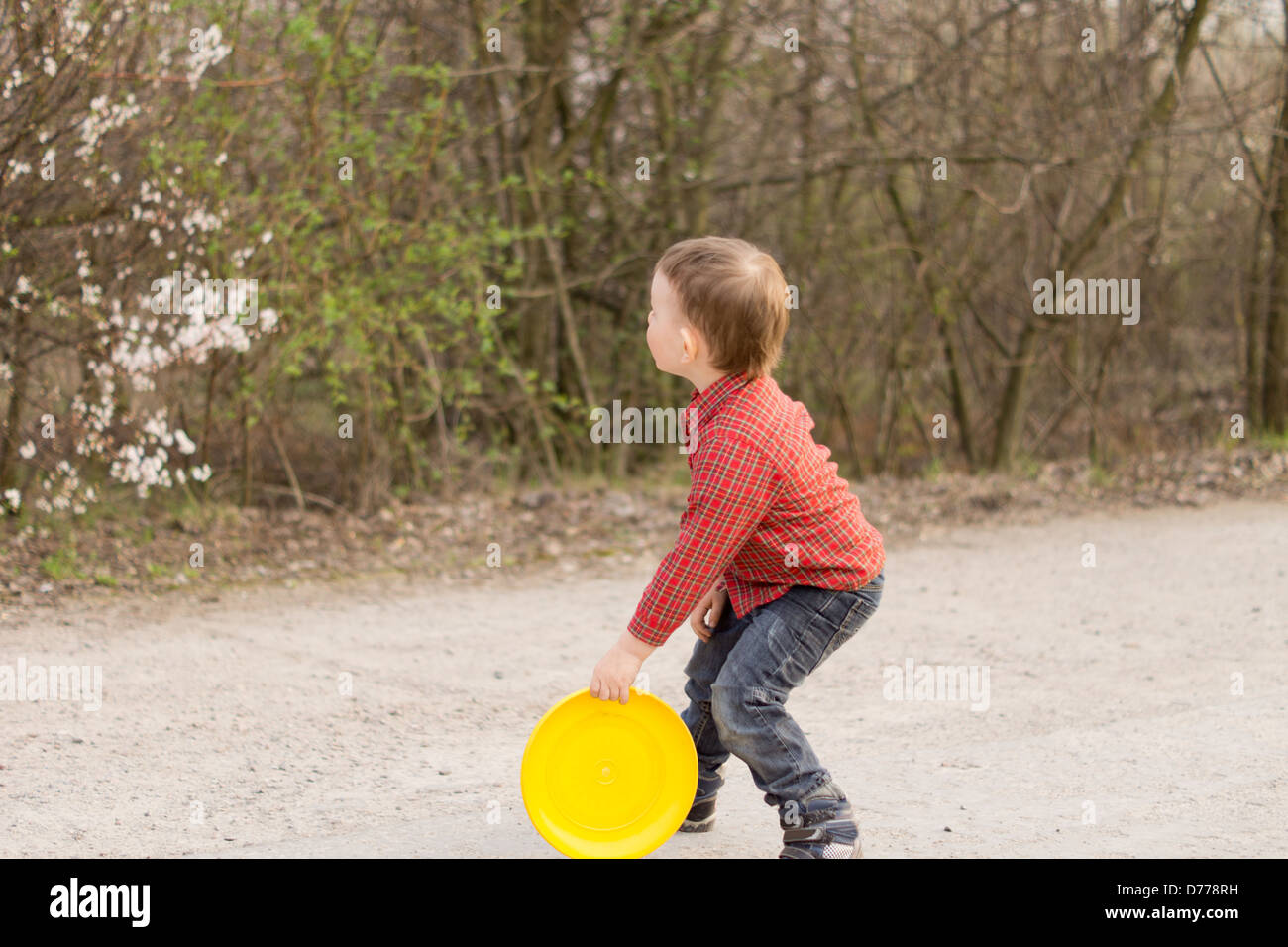 Little boy preparing to throw a bright yellow plastic frisbee looking ...