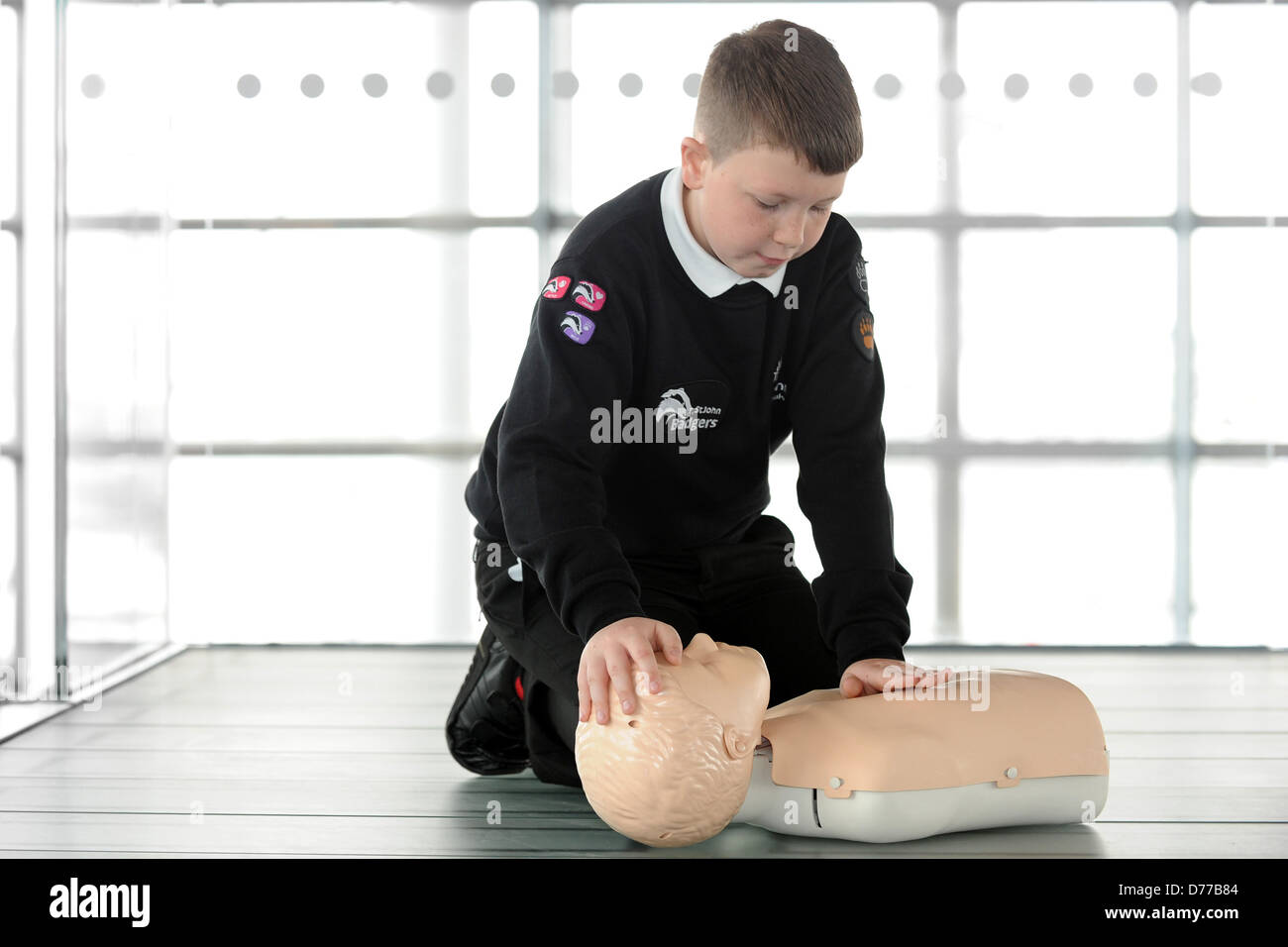 A young boy practices life saving first aid on a dummy for St. John ...