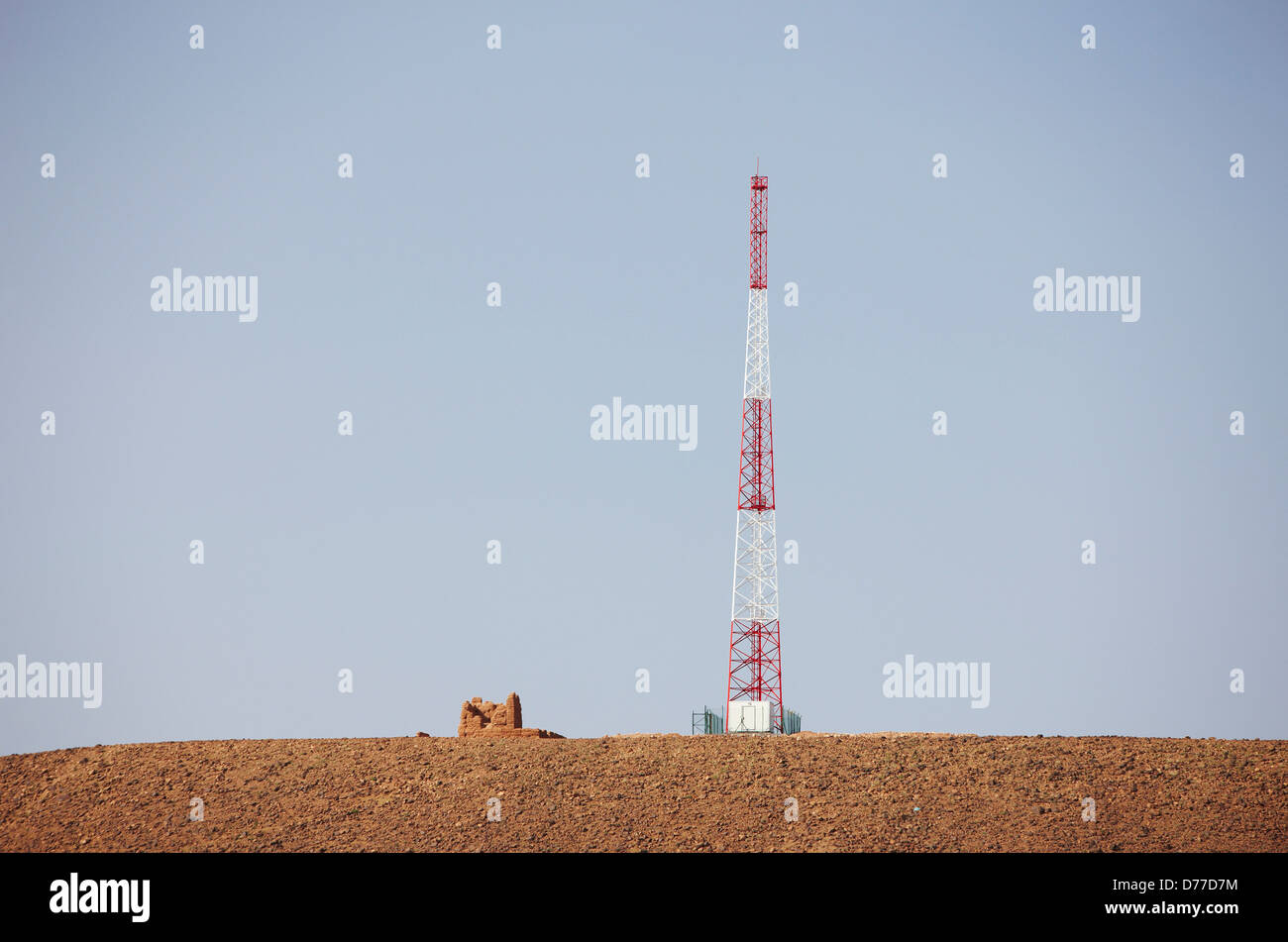 Modern radio wave relay tower stands next to ancient decaying earthen ...