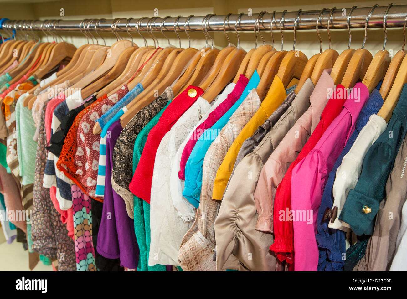 Various multi-colored items of clothing hanging on hangers and rail in ...