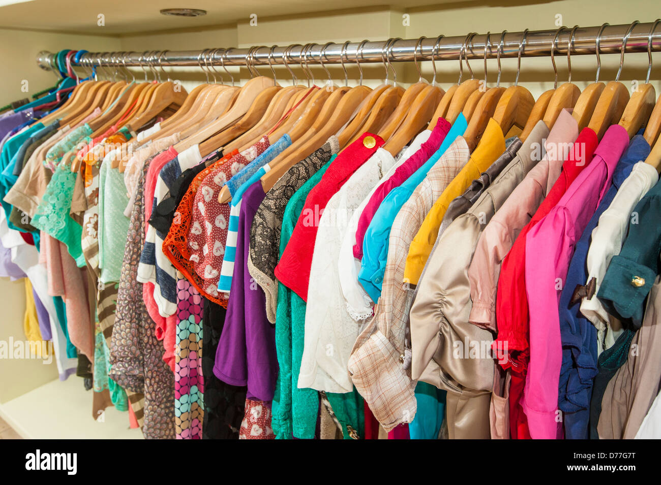 Various multi-colored items of clothing hanging on hangers and rail in ...