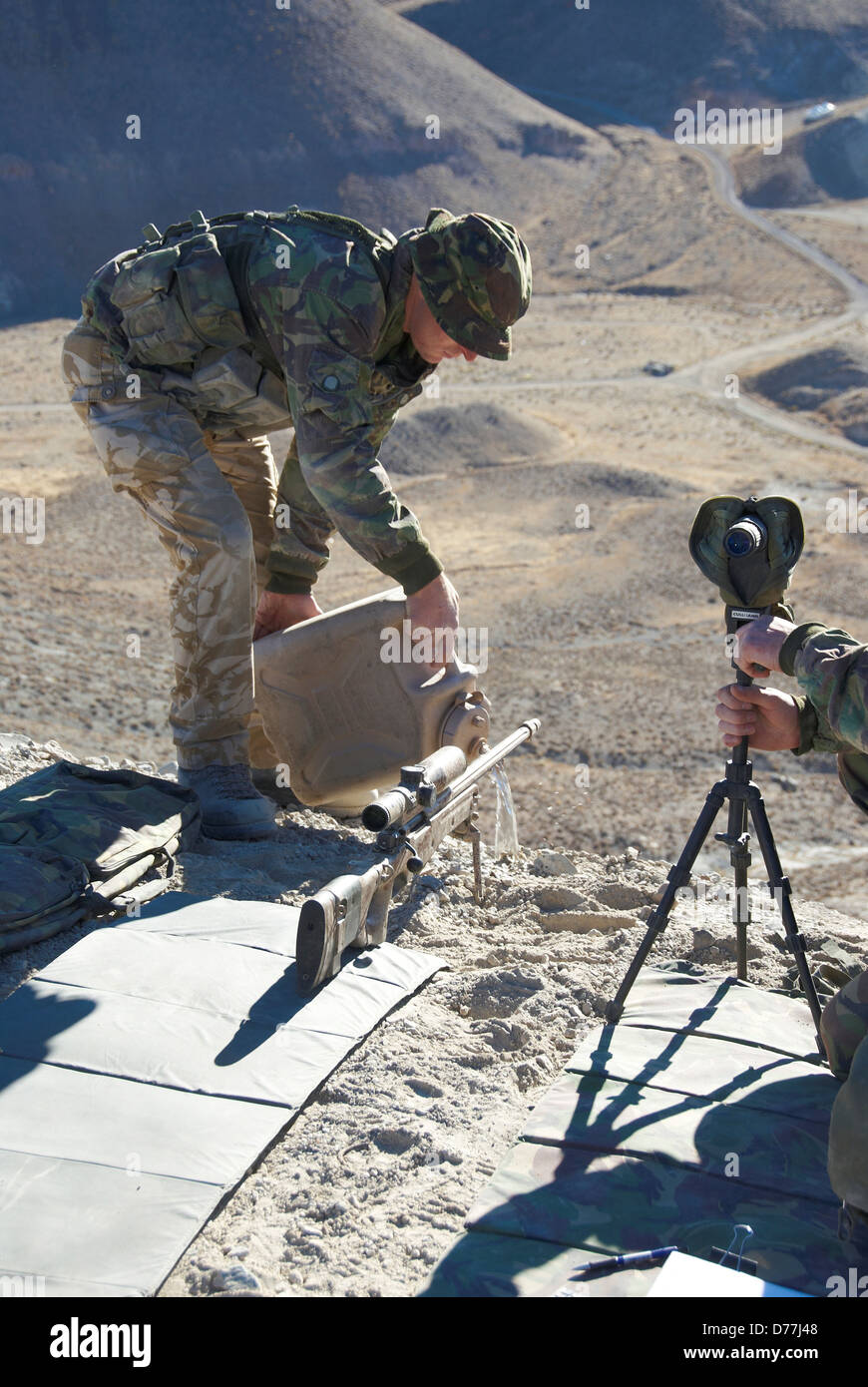 British Royal Marine pours water on dirt below muzzle sniper rifle to ...