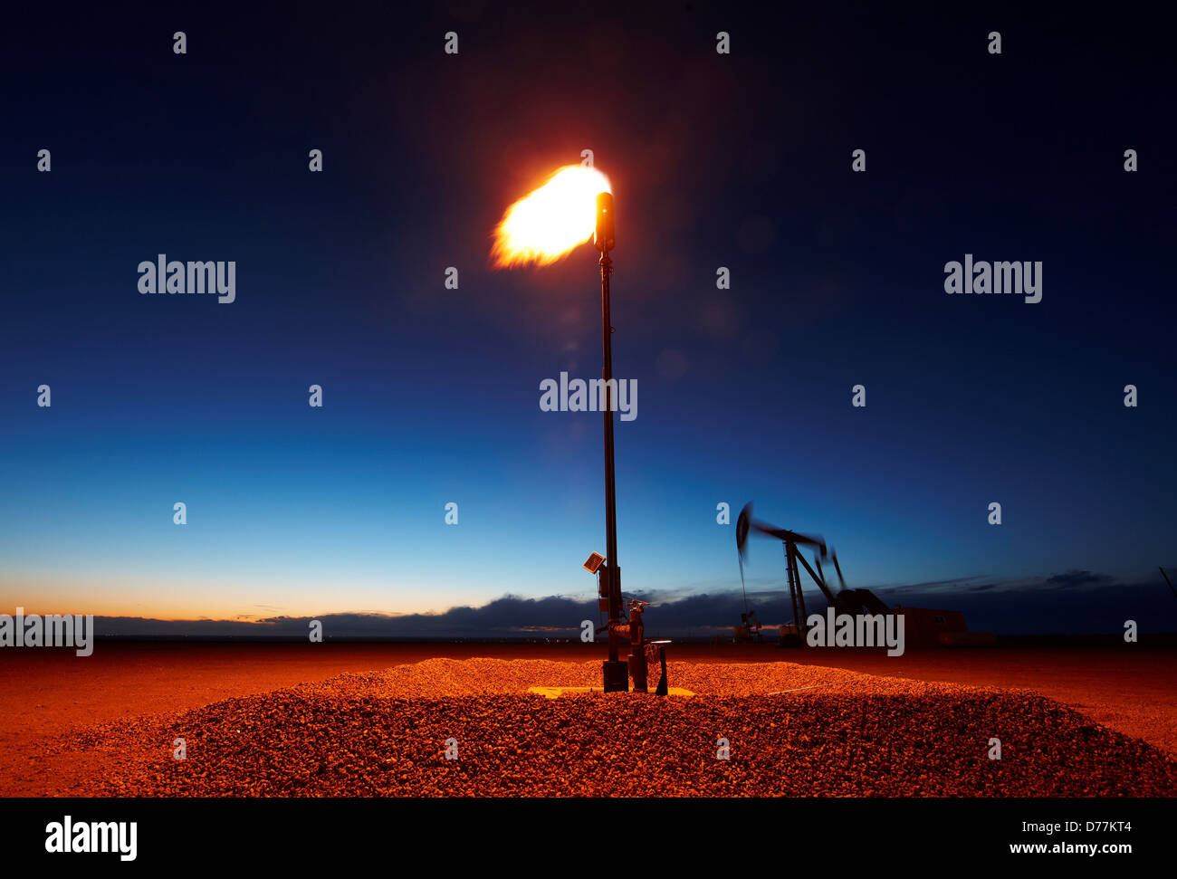 Oil well pumpjack pump jack in background gas flare flare stack in ...