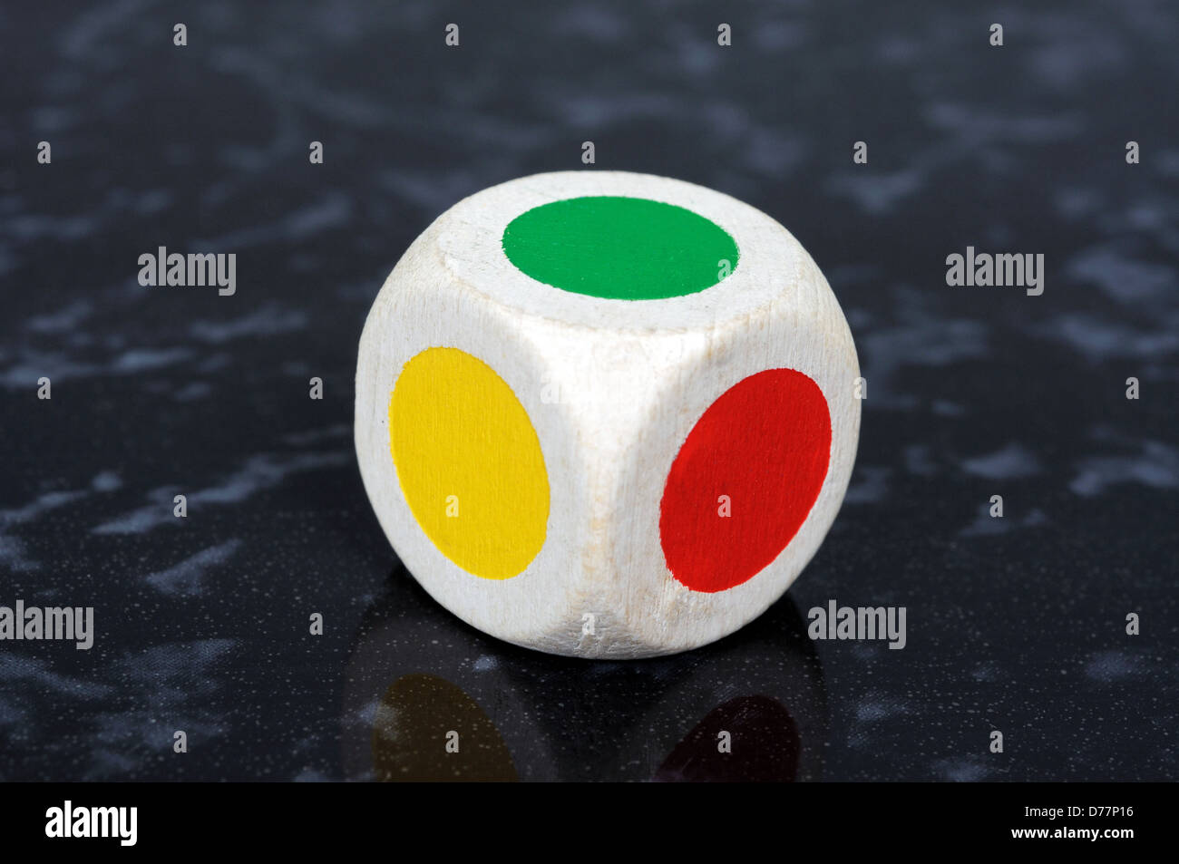 Standard six sided die with coloured spots against a black background ...
