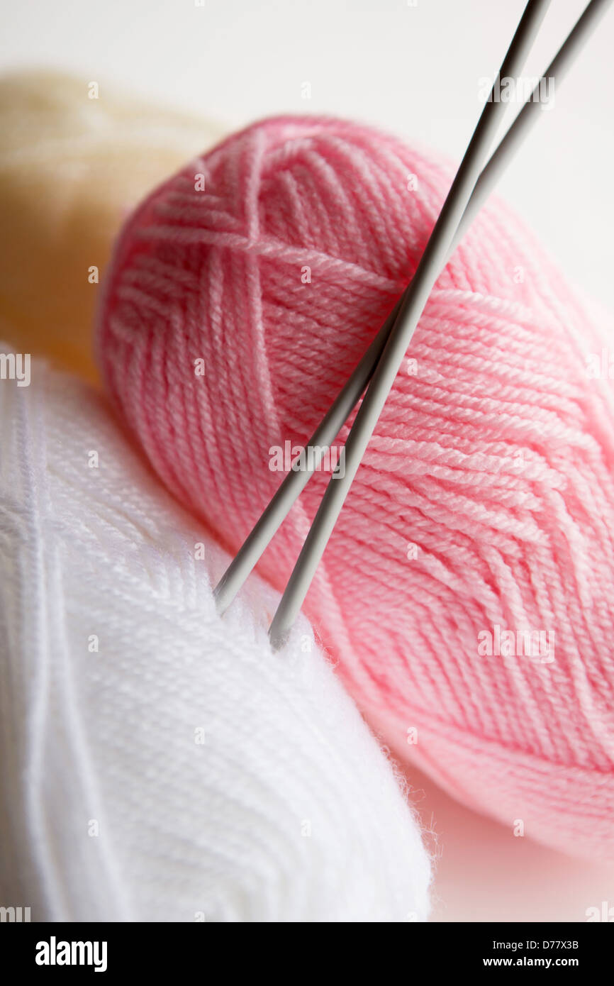 Three balls of wool with a set of knitting needles placed in one ball ...