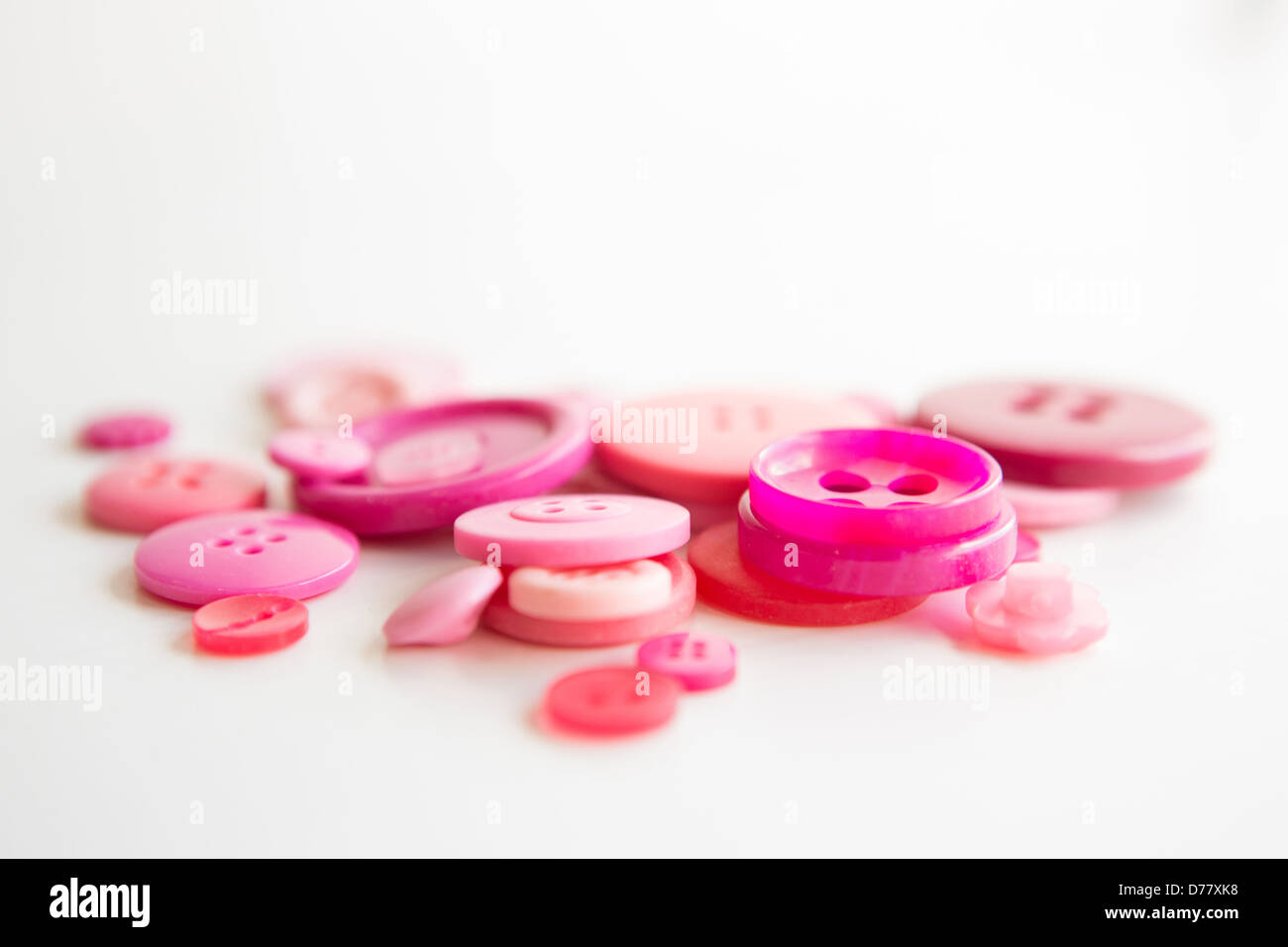 A handful of pink buttons on a light grey background Stock Photo - Alamy