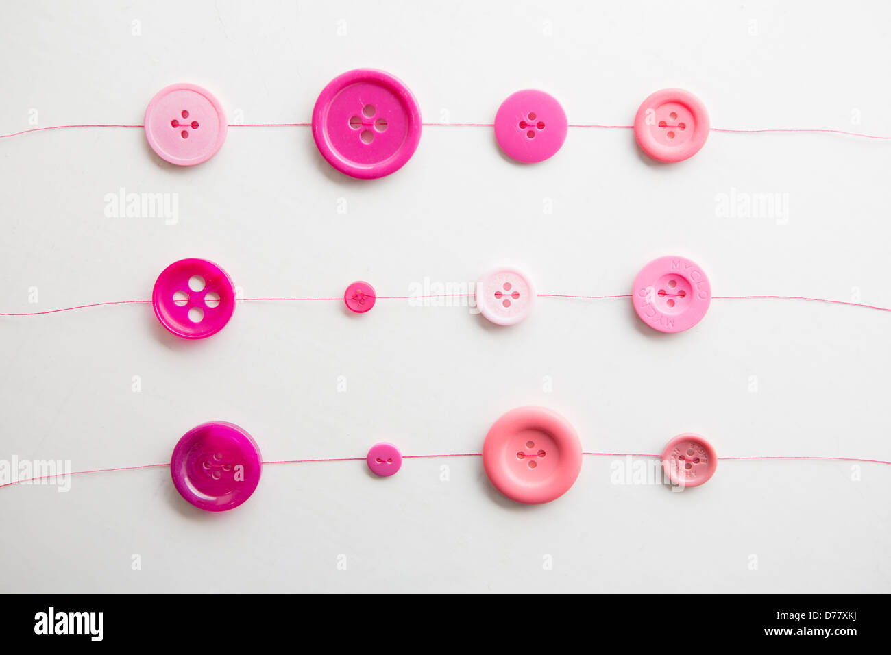 Pink buttons threaded and placed in lines Stock Photo - Alamy