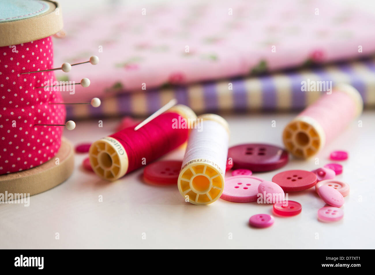 A sewing kit of thread, pins, pin cushion, fabric, and buttons ...