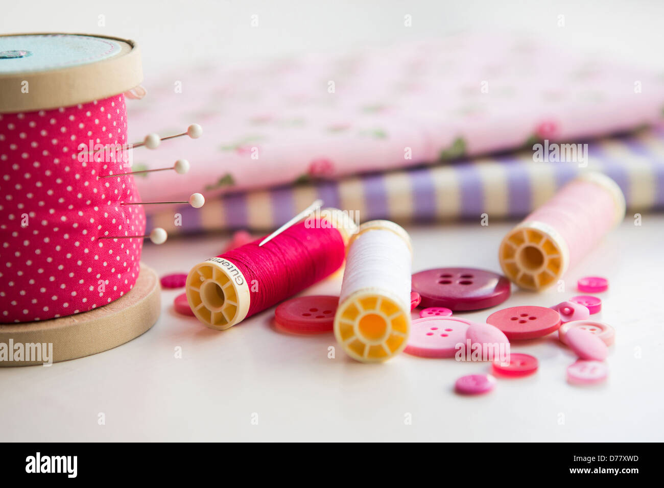 A sewing kit of thread, pins, pin cushion, fabric, and buttons ...