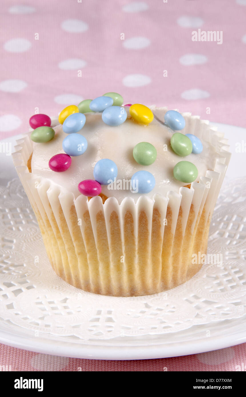 cupcake with icing and colorful sweets on a plate Stock Photo - Alamy