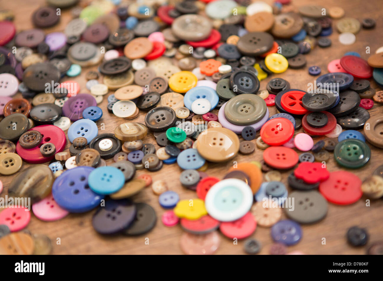 A selection of buttons scattered across a wooden floor Stock Photo - Alamy