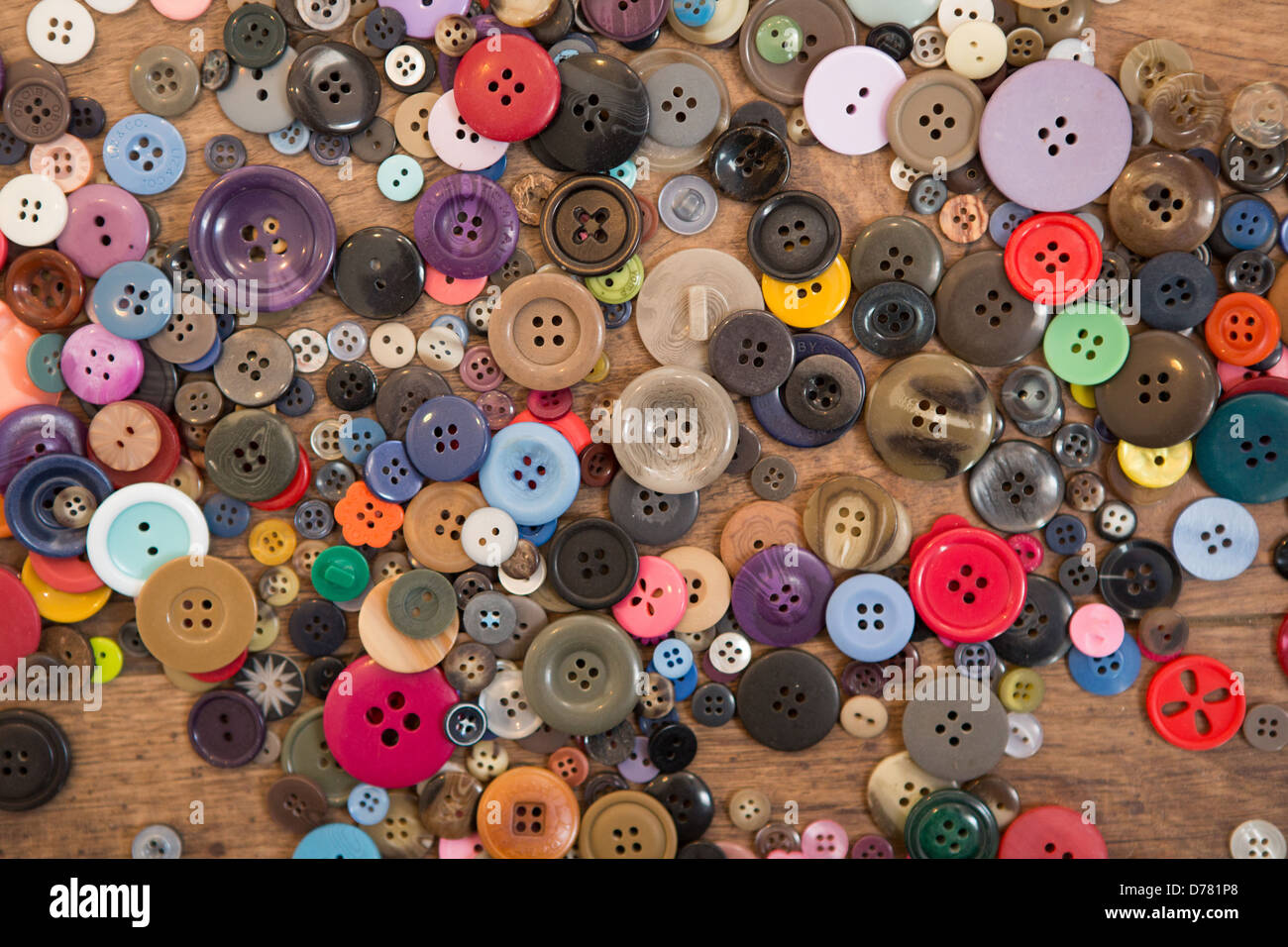 A selection of buttons scattered across a wooden floor Stock Photo - Alamy
