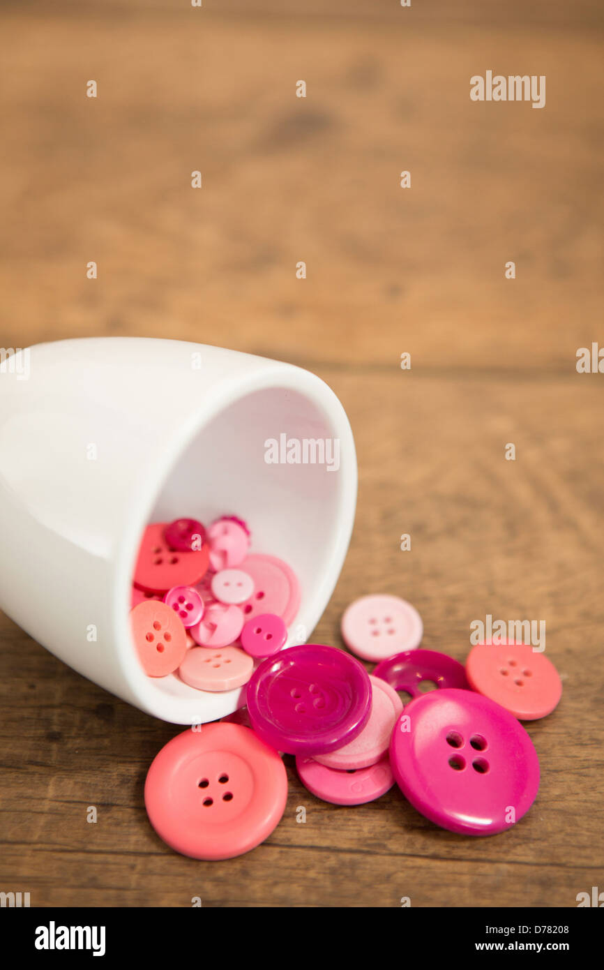 A handful of pink buttons spilling from a small white bowl Stock Photo ...