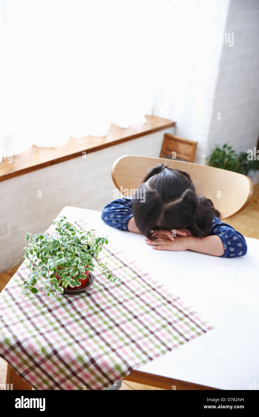 a girl sleeping while sitting at table Stock Photo - Alamy