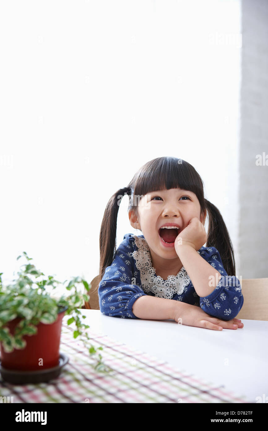 a girl laughing while sitting at table Stock Photo - Alamy