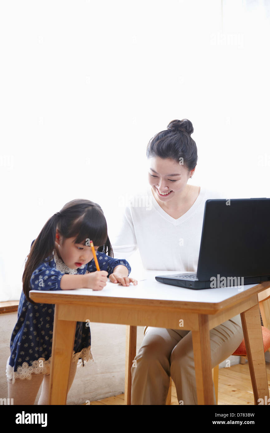 mother helping daughter write on paper Stock Photo - Alamy