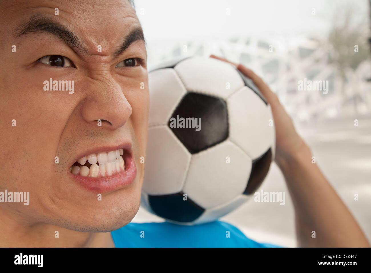 Close up of angry young man holding a soccer ball Stock Photo - Alamy