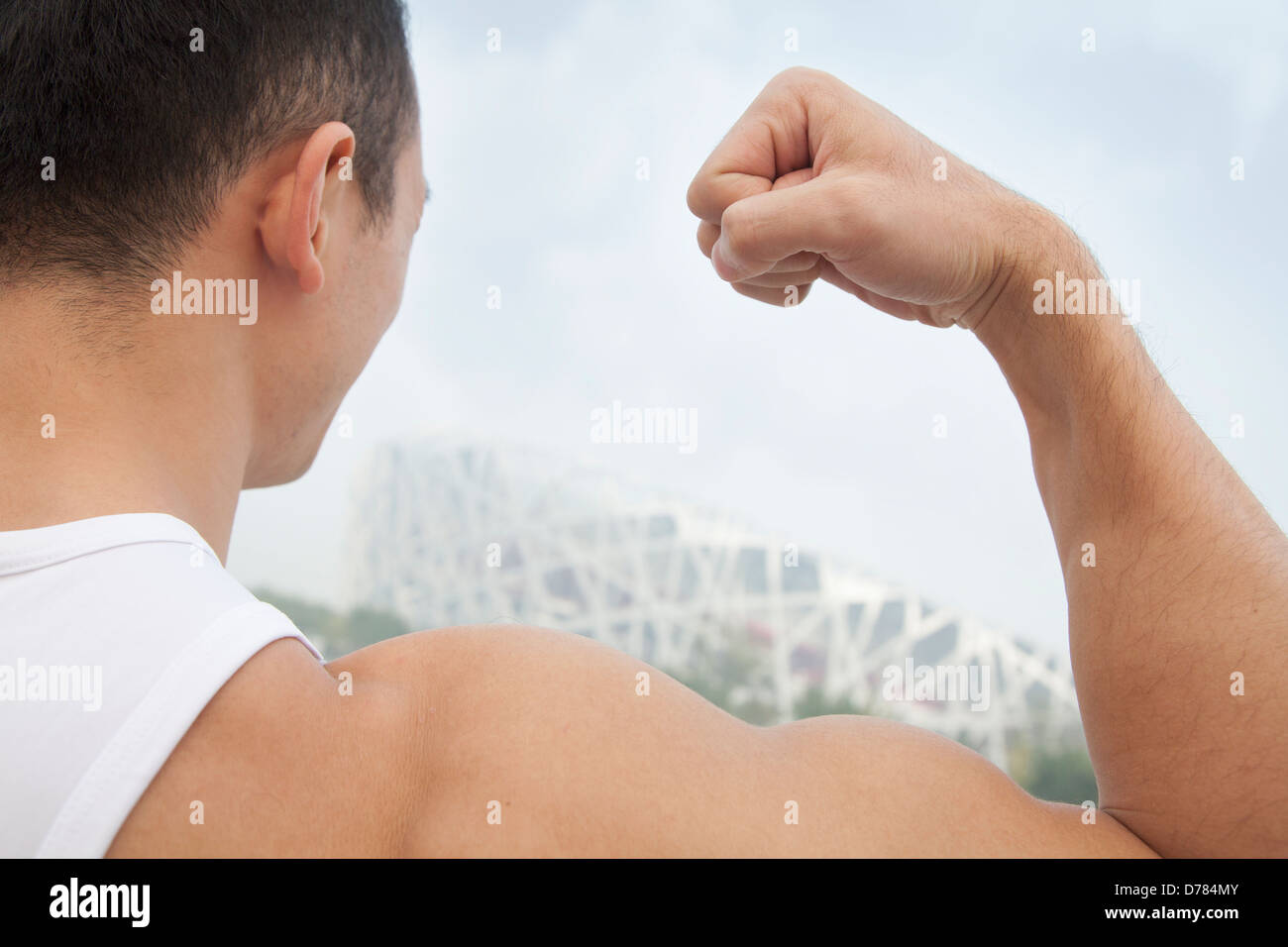 Rear view of young man flexing his bicep, tilt Stock Photo - Alamy