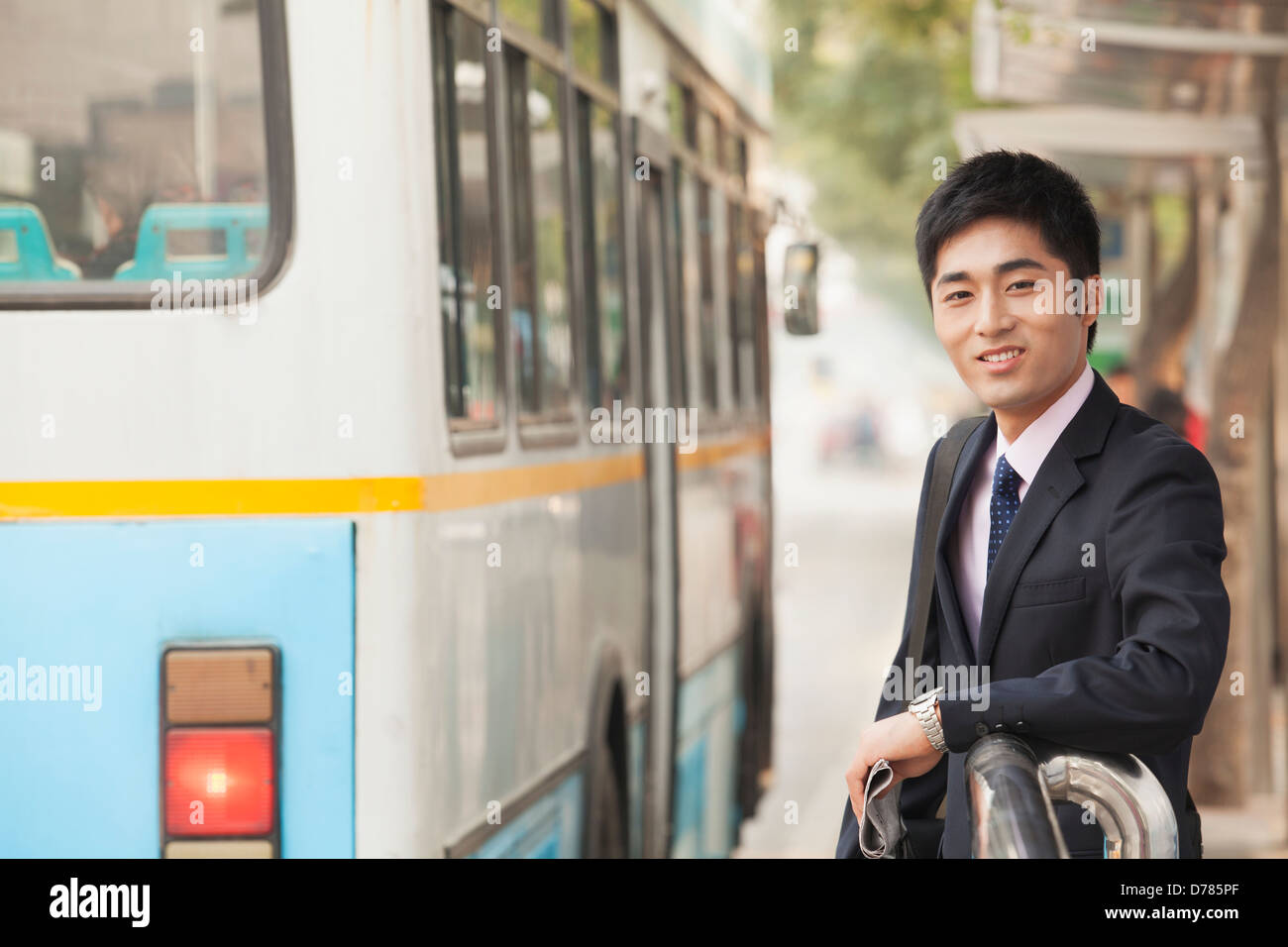 Young businessman waiting at the bus stop for the bus Stock Photo - Alamy