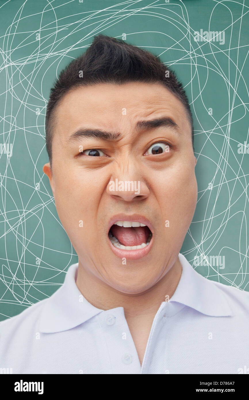 Young student in front of blackboard, making a face Stock Photo - Alamy