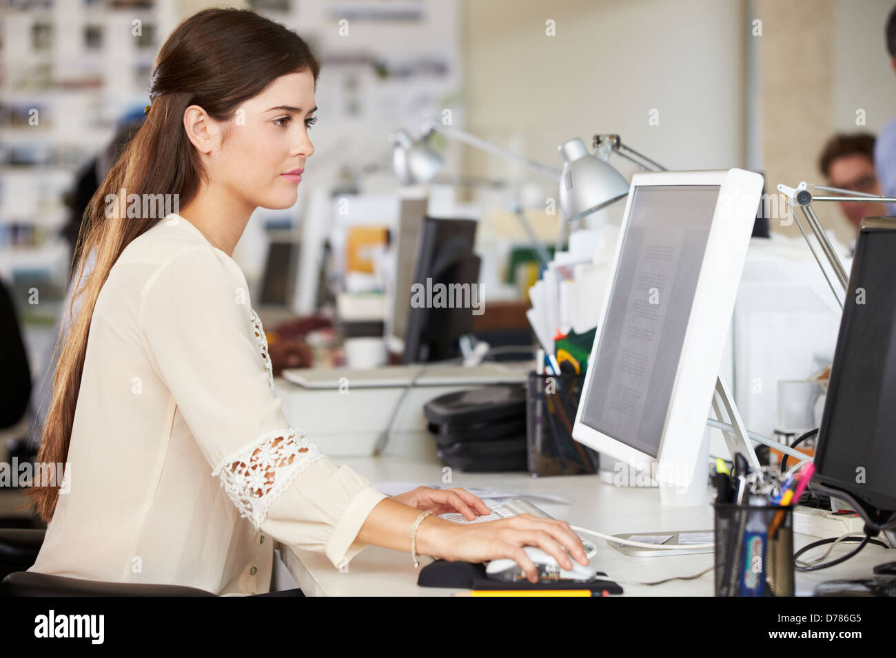 Woman Working At Desk In Busy Creative Office Stock Photo - Alamy