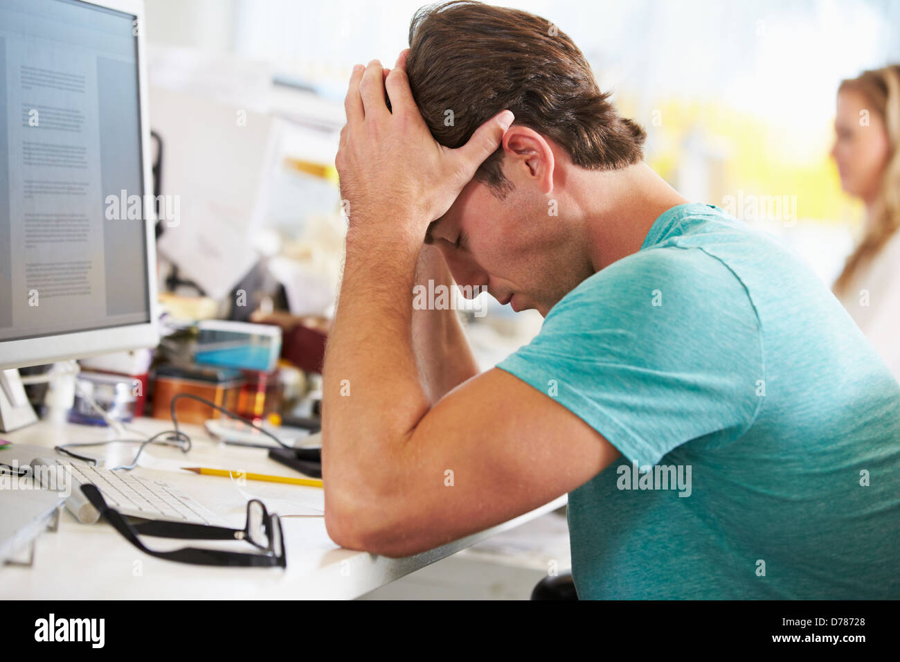 Stressed Man Working At Desk In Busy Creative Office Stock Photo - Alamy