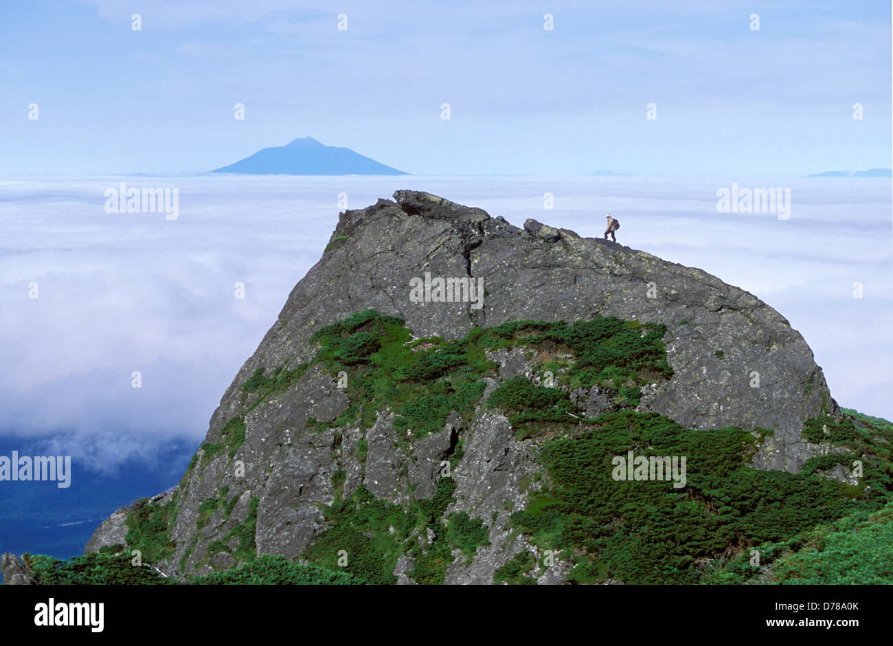 Hiker atop Mendelevo volcano; Tyatya volcano in background looming ...