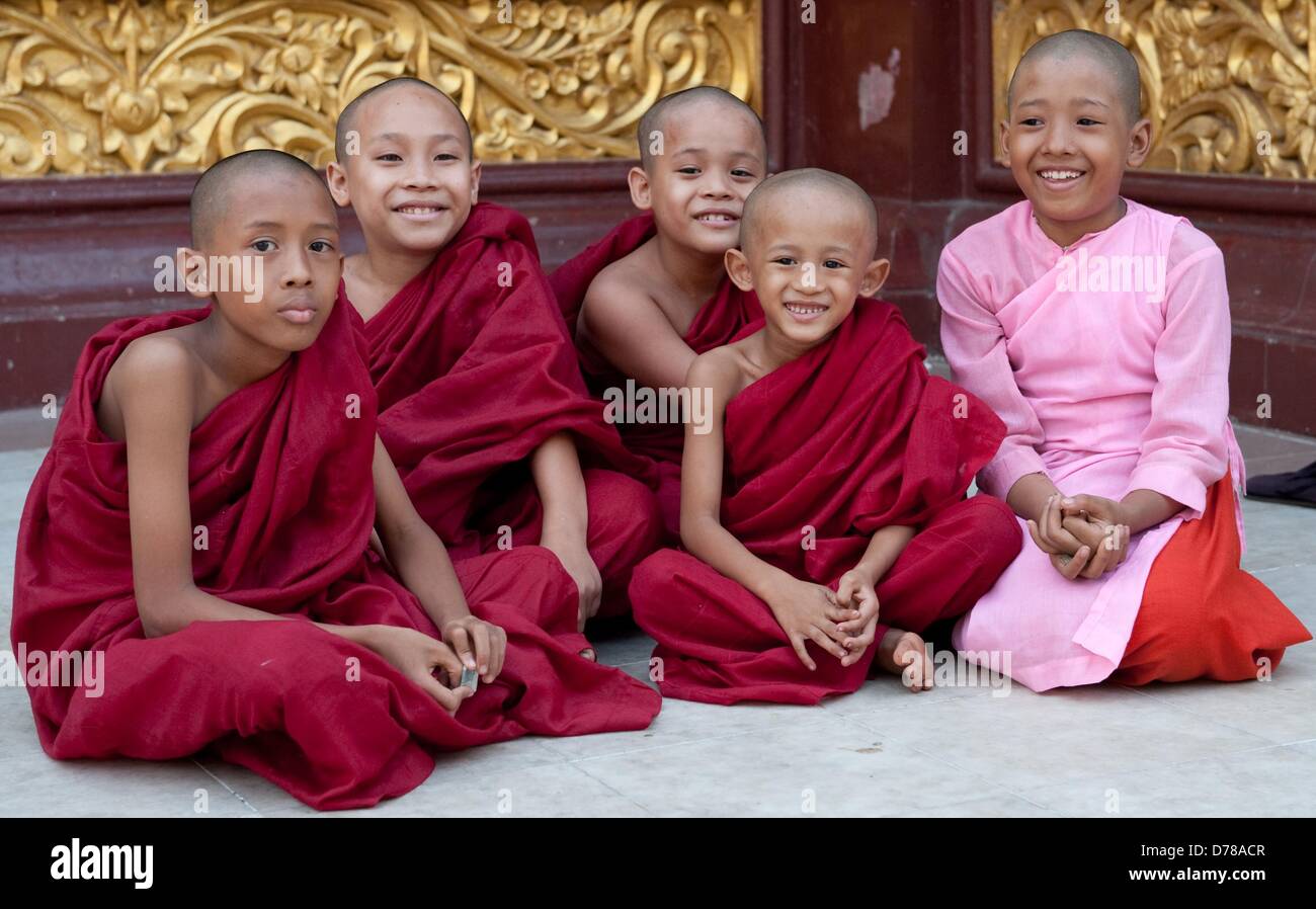 Myanmar Young Buddhist monks and a Buddhist nun are sitting together at ...