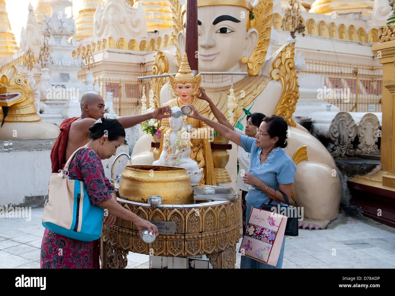 Believers pour water over a Buddha statue at the Shwedagon Pagoda in ...