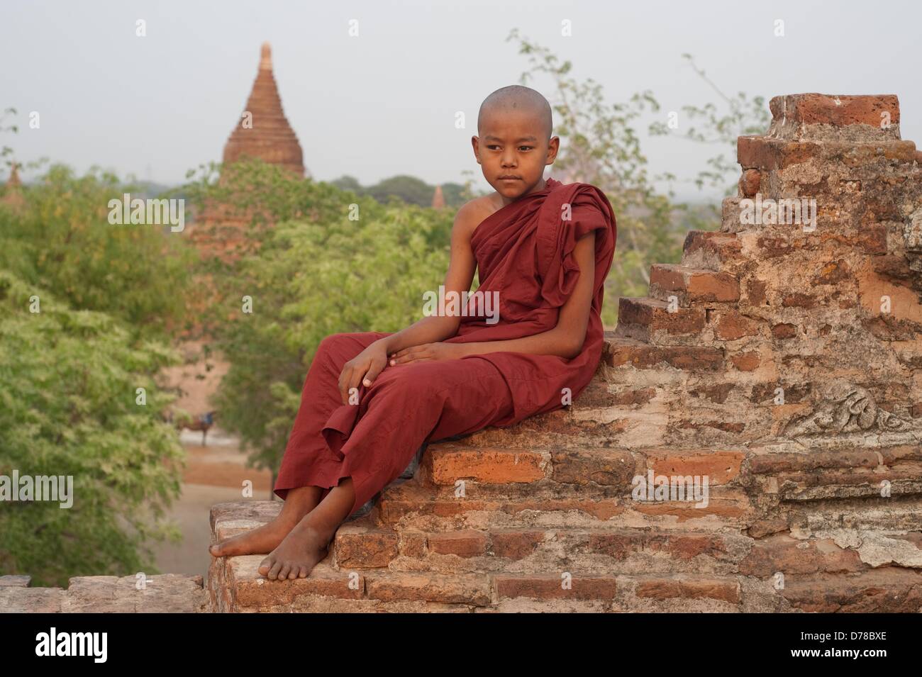 A young Buddhist monk is holding a candle in a temple in Bagan, Myanmar ...