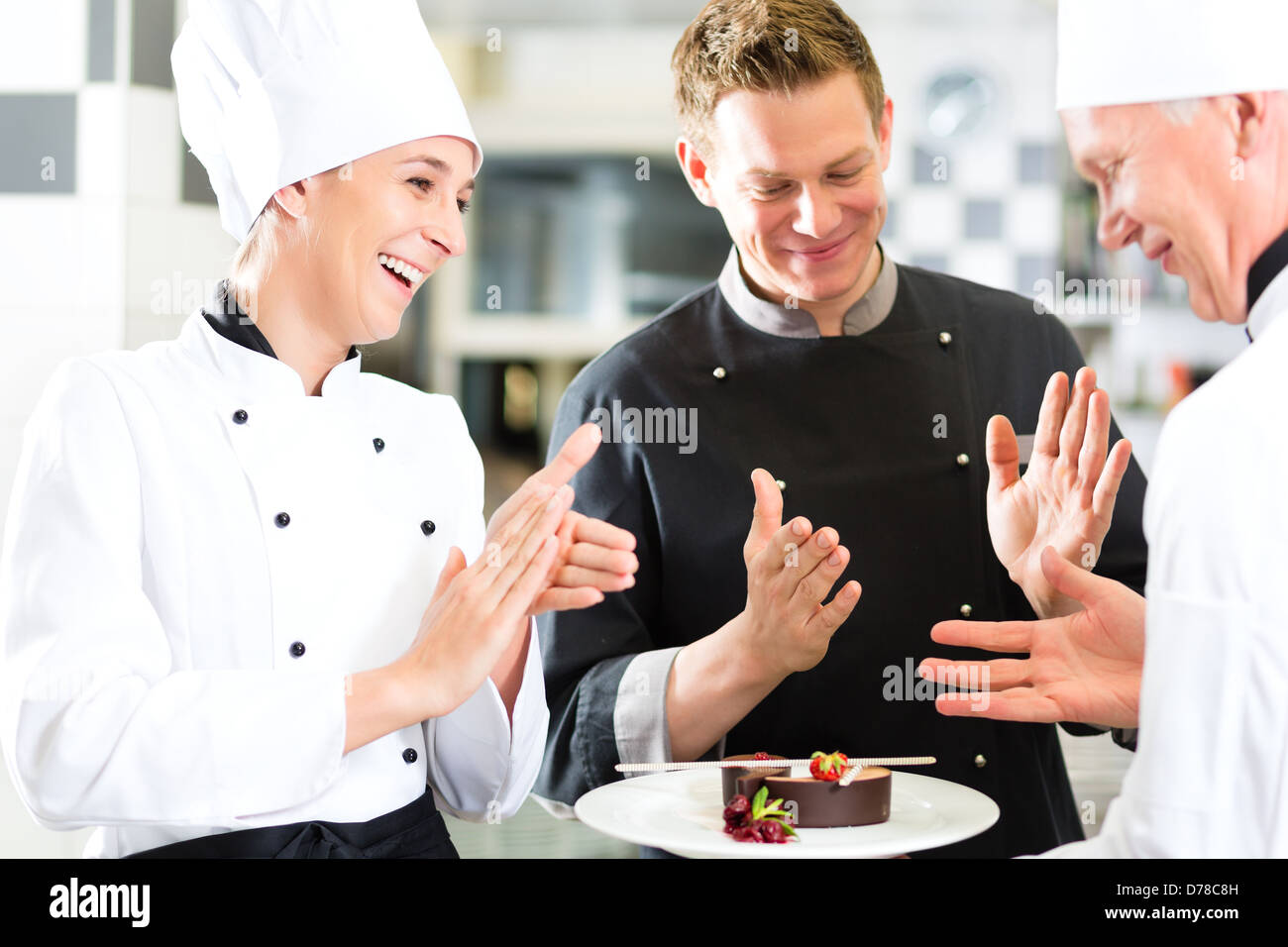 Chef team in restaurant kitchen with dessert, the colleagues applauding ...