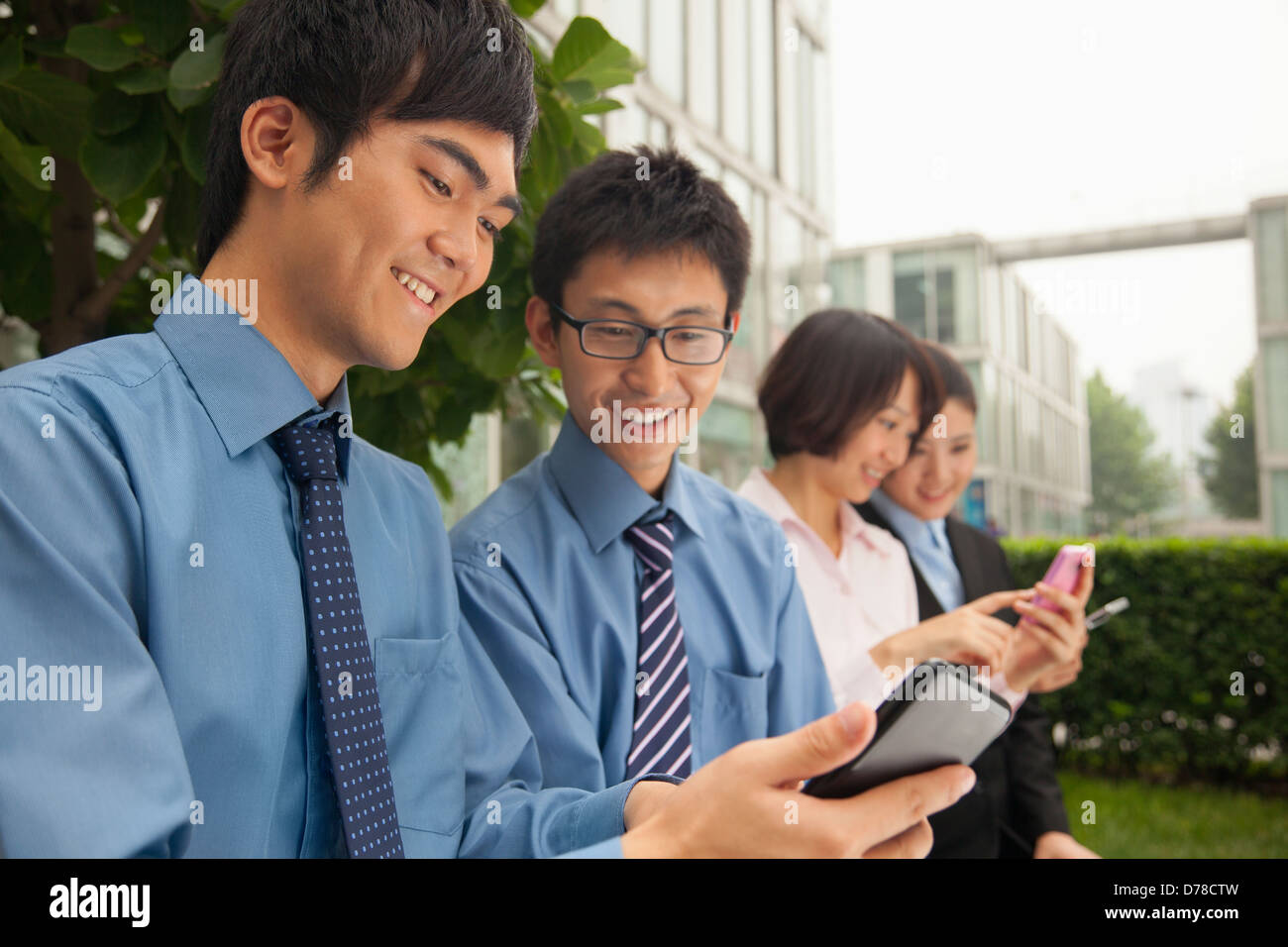 Young business people checking their cell phones Stock Photo - Alamy