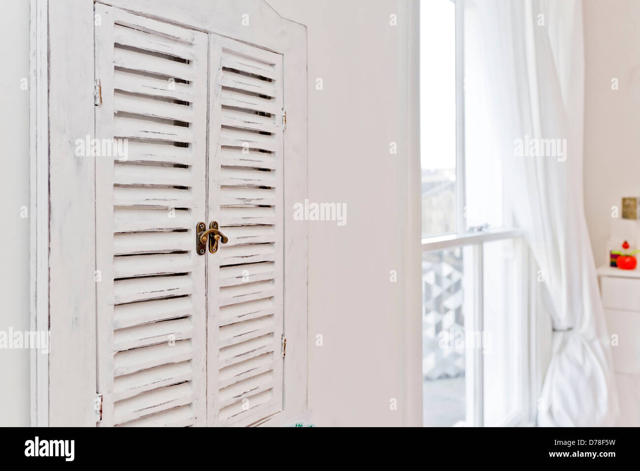 Distressed cupboard shutters and sash window in modern white room Stock ...