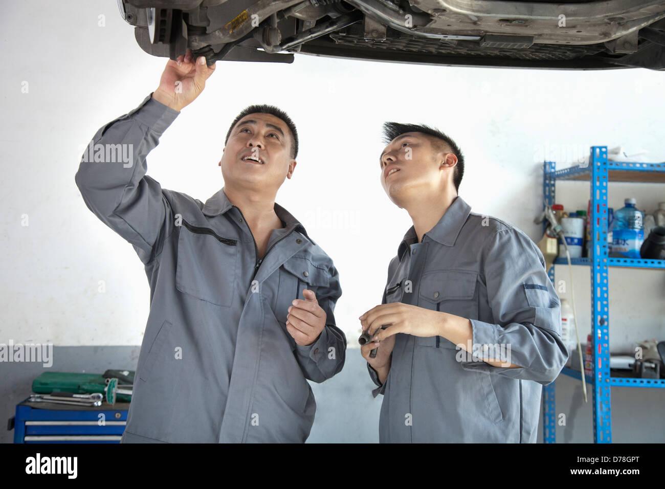 Two Mechanics Looking at Underside of a Car Stock Photo - Alamy