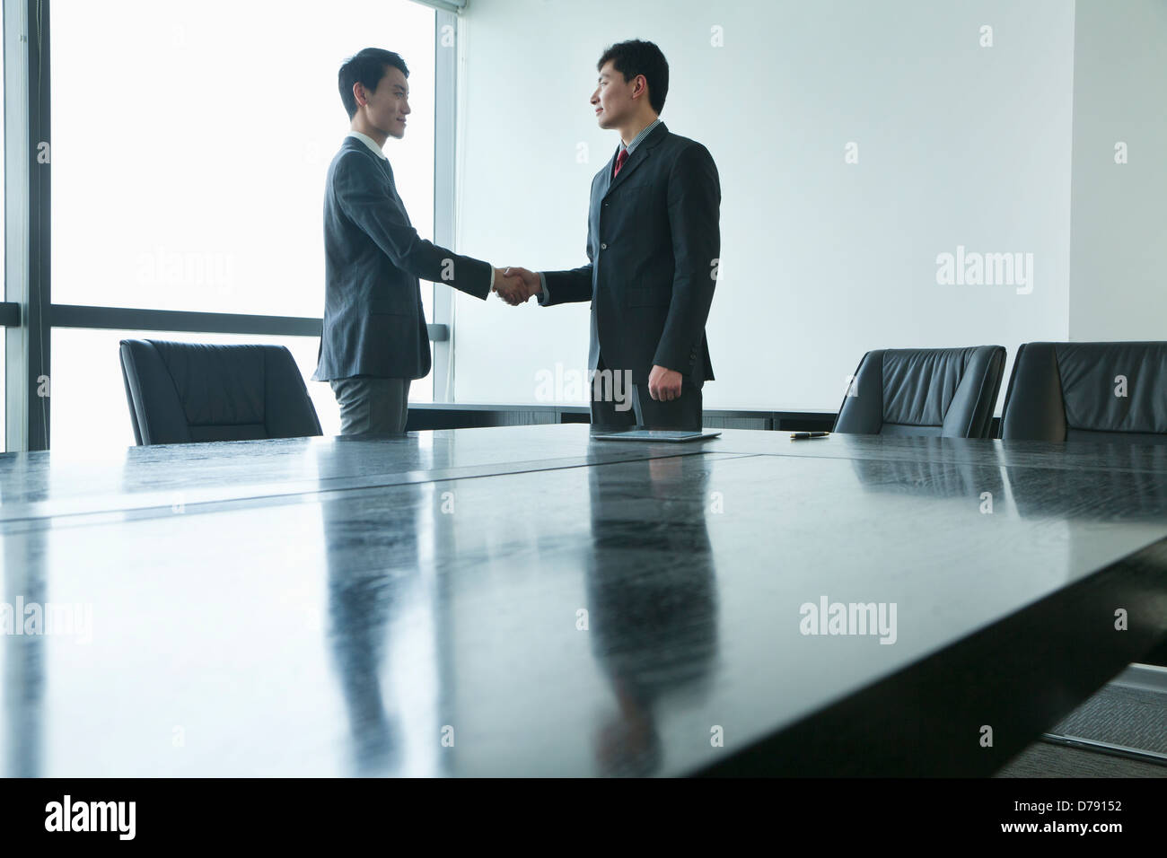 Businessmen shaking hands in meeting room Stock Photo - Alamy