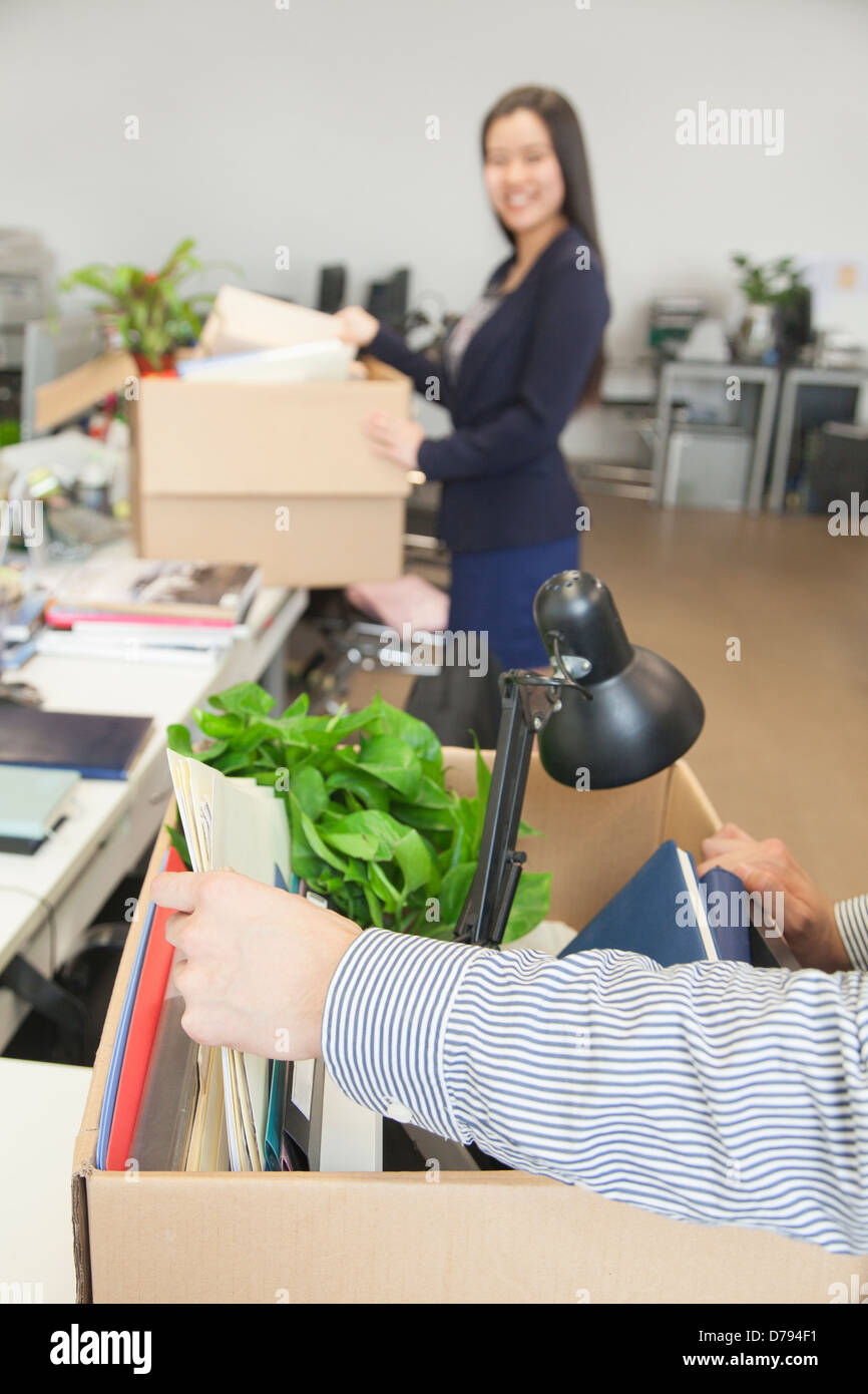 Two young business people carrying boxes with office items Stock Photo ...