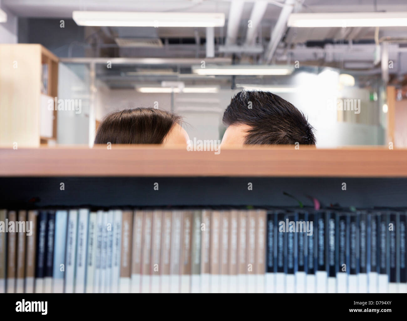 Work romance between two business people hiding behind shelves Stock ...