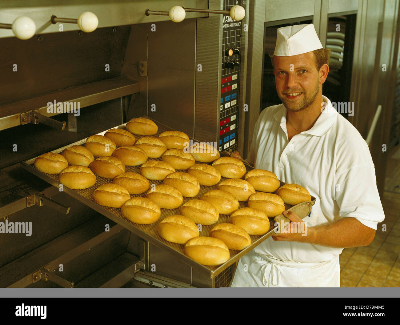 Baker removing rolls oven Stock Photo - Alamy