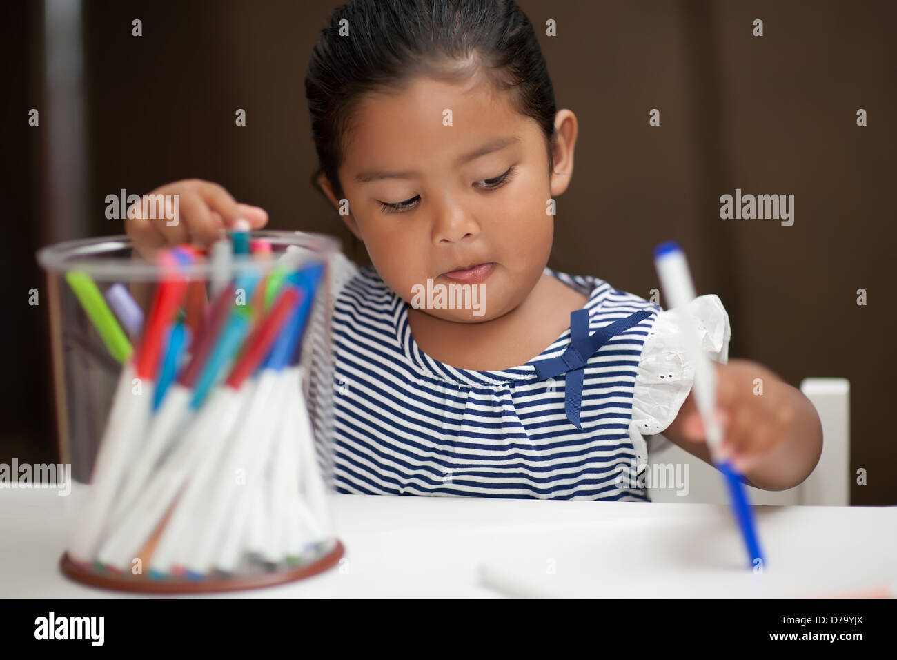 Toddler learning to color and draw with markers on white table Stock ...
