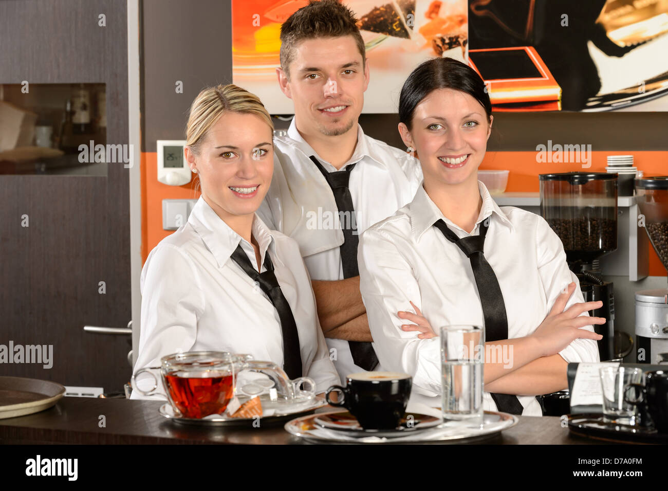Three smiling server posing in uniform in cafe Stock Photo - Alamy
