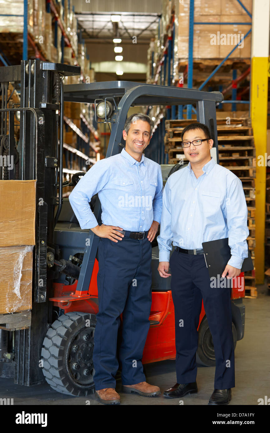 Portrait Of Businessmen With Fork Lift Truck In Warehouse Stock Photo ...