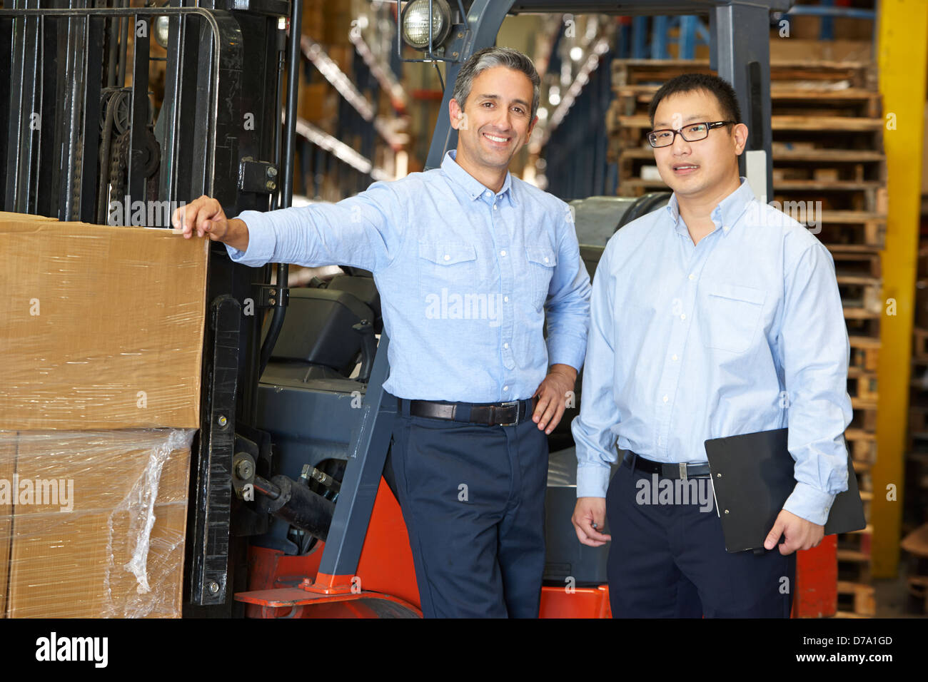Portrait Of Businessmen With Fork Lift Truck In Warehouse Stock Photo ...