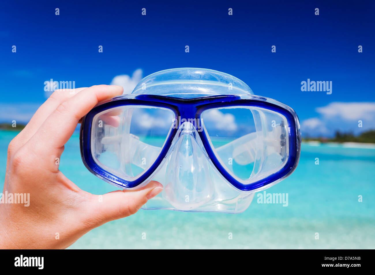 Hand holding snorkel googles against beach and sky Stock Photo - Alamy