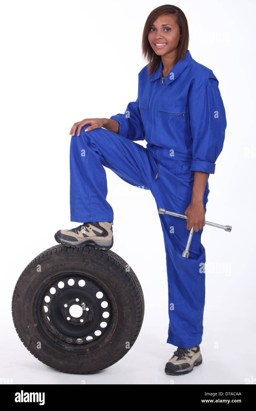 Young African woman as a mechanic apprentice with car tires in the car ...