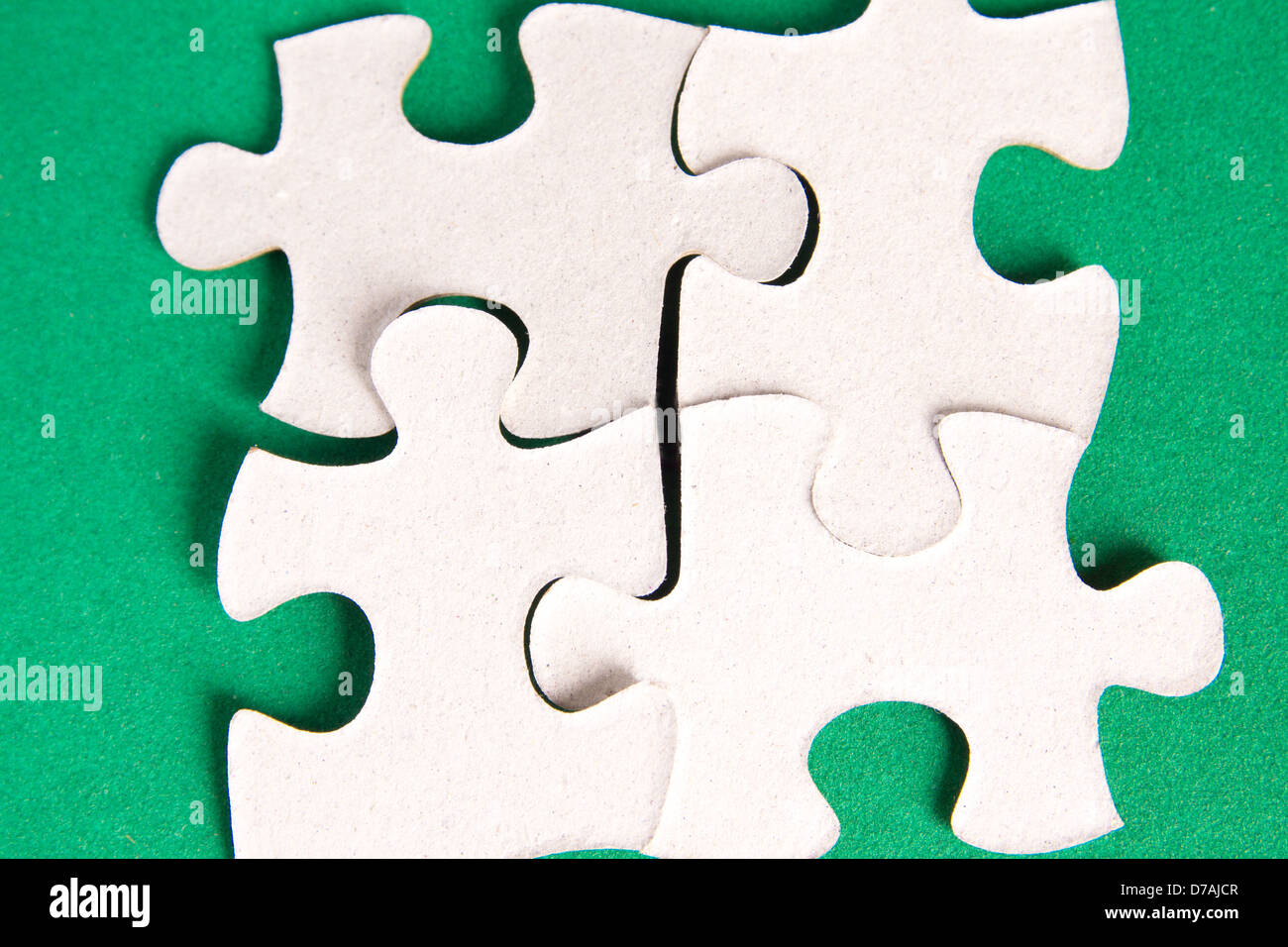Puzzle four pieces on green background close up Stock Photo - Alamy