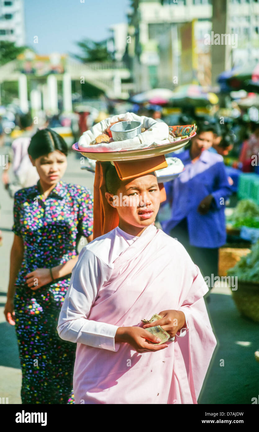 Young Buddhist nun in pink robes in a busy street in Mandalay, Burma ...