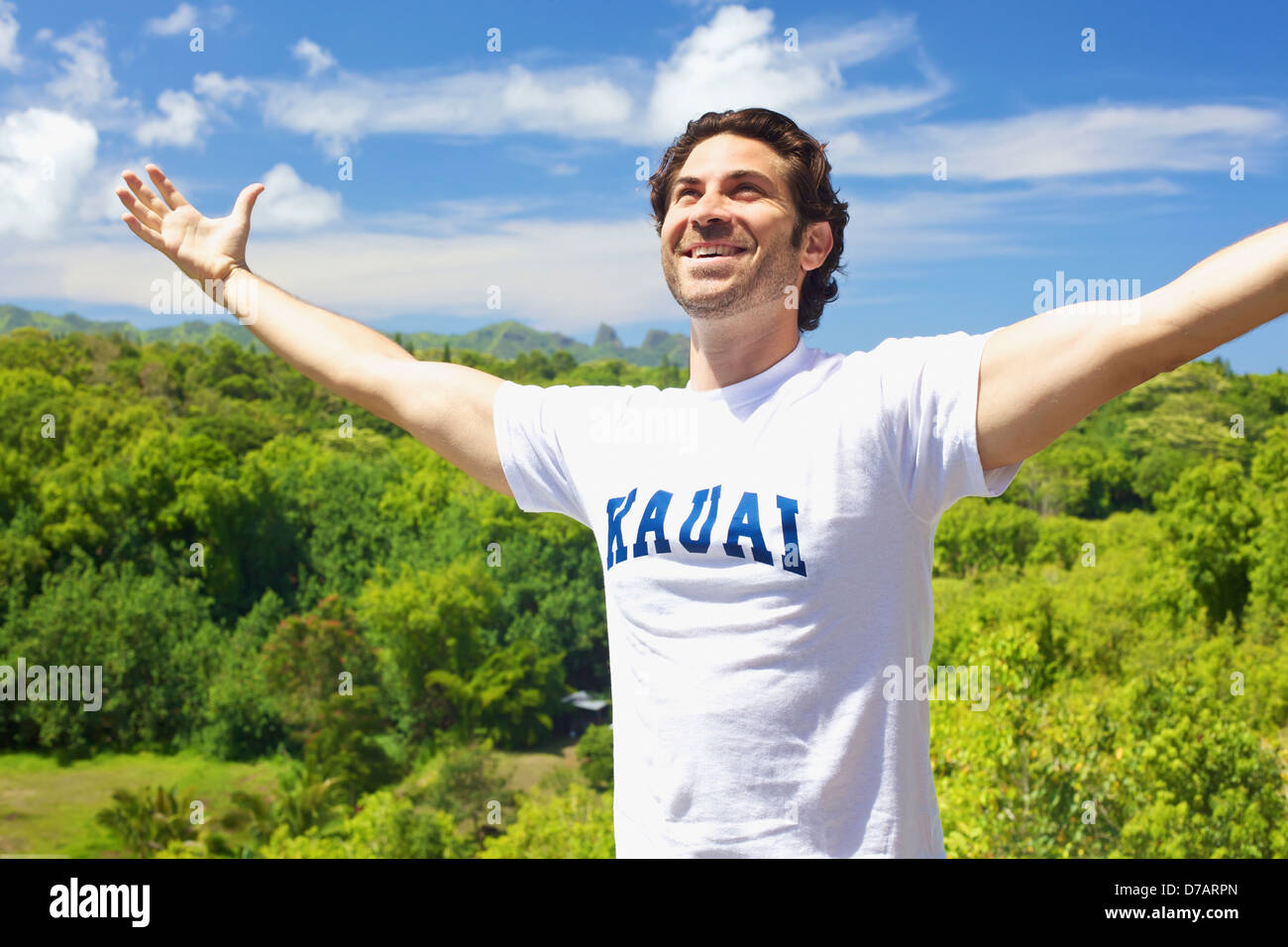 A Smiling Man Stands With Arms Raised And Lush Vegetation In The ...