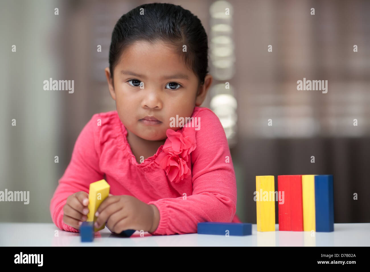 Toddler holding building block with thoughtful look Stock Photo - Alamy