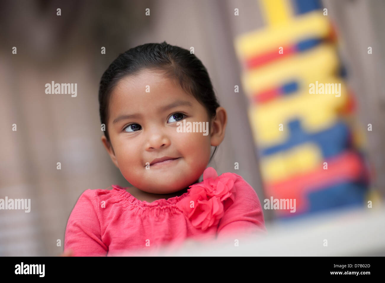 Cute girl with thoughtful look and building block tower in foreground ...